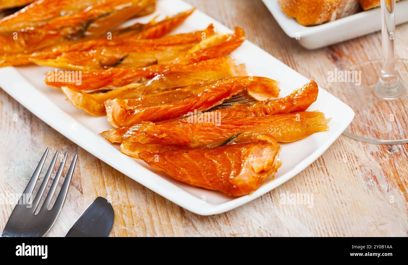 Smoked salmon belly strips on plate on wooden table Stock Photo - Alamy
