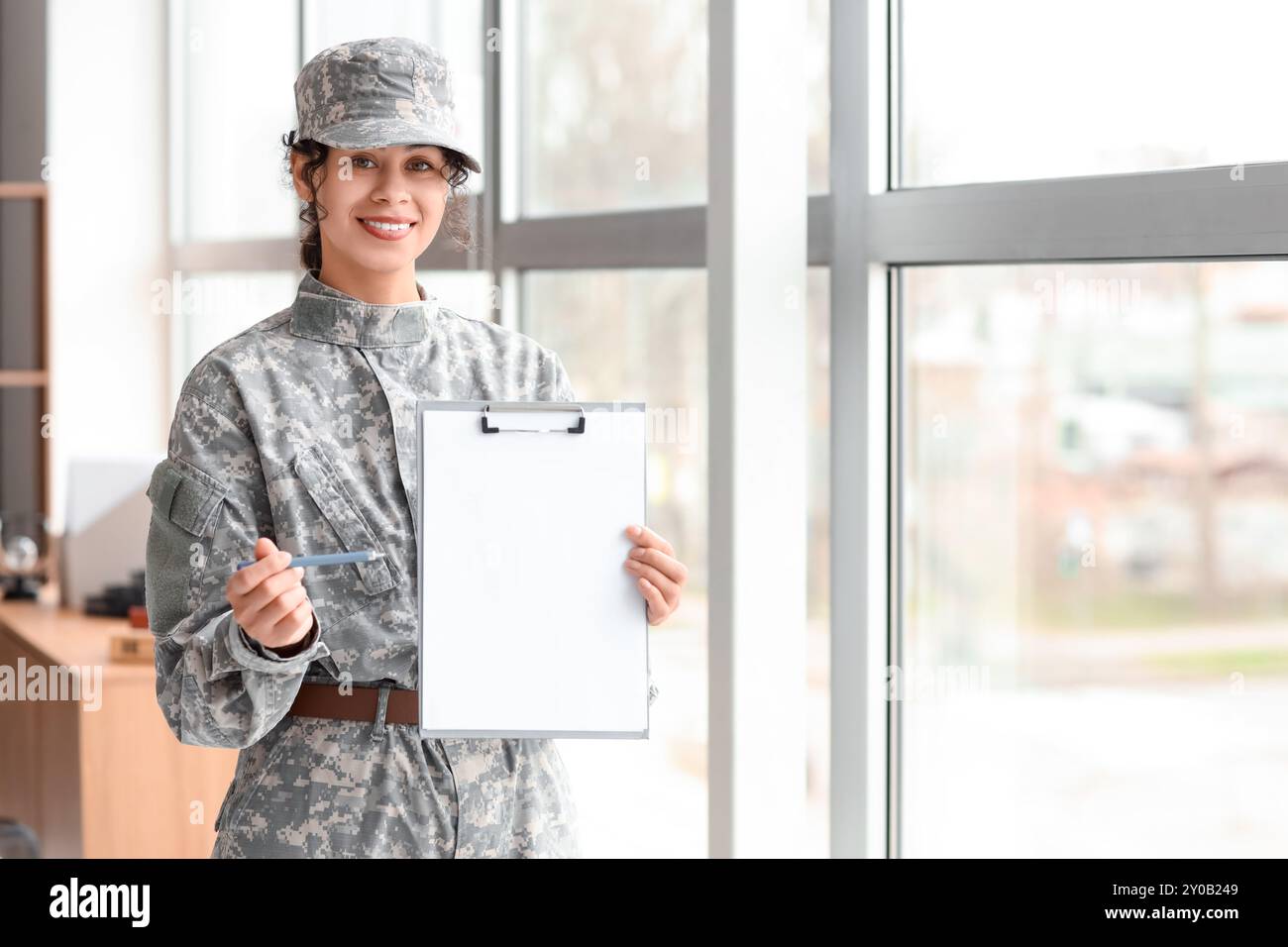 Female African-American soldier with clipboard near window at ...