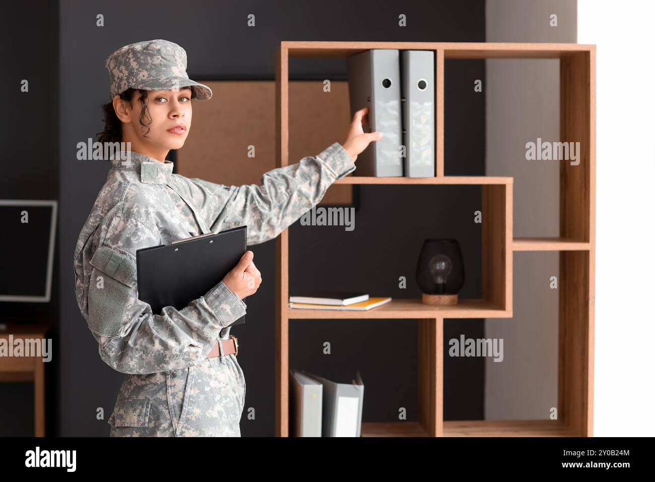 Female African-American soldier taking folder from shelf at ...
