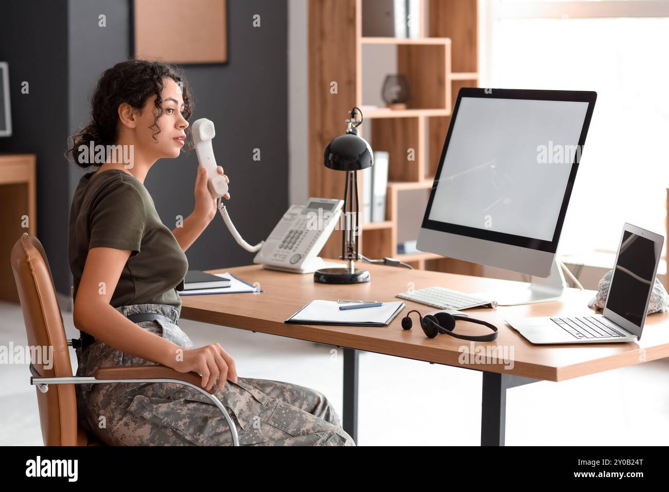 Female African-American soldier talking by telephone at table in ...