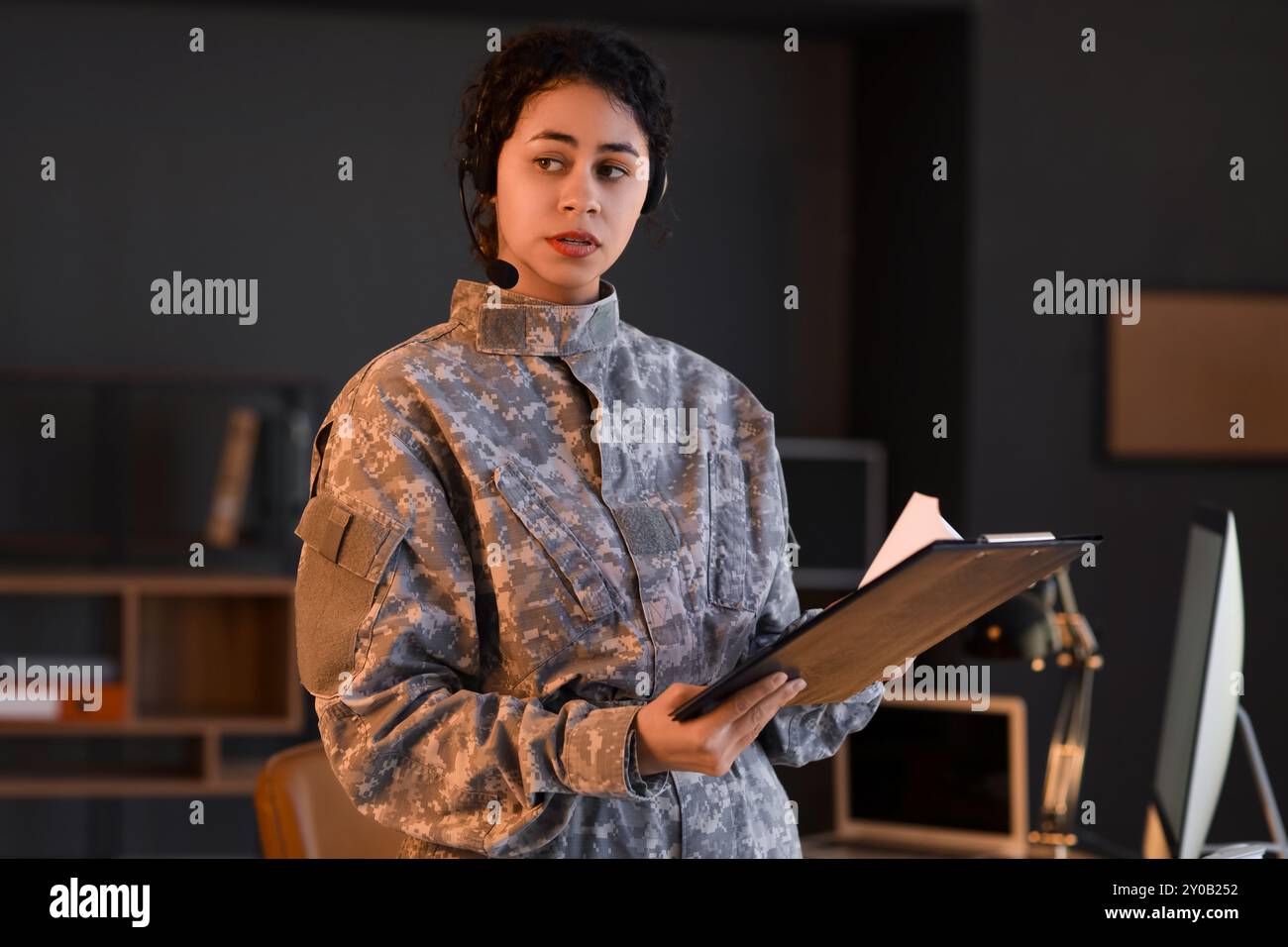 Female African-American soldier with headset and clipboard in ...