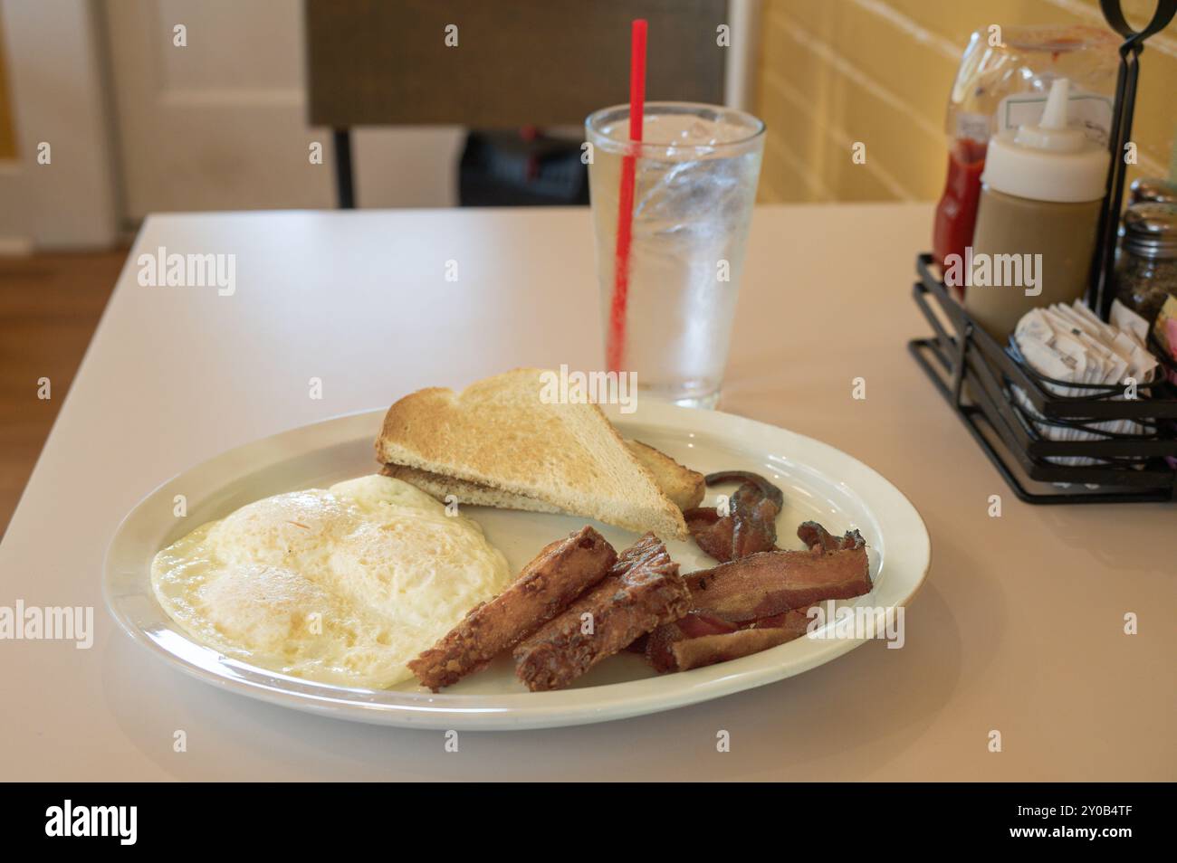 Breakfast of eggs, bacon, toast and hash brown cakes with water Stock ...