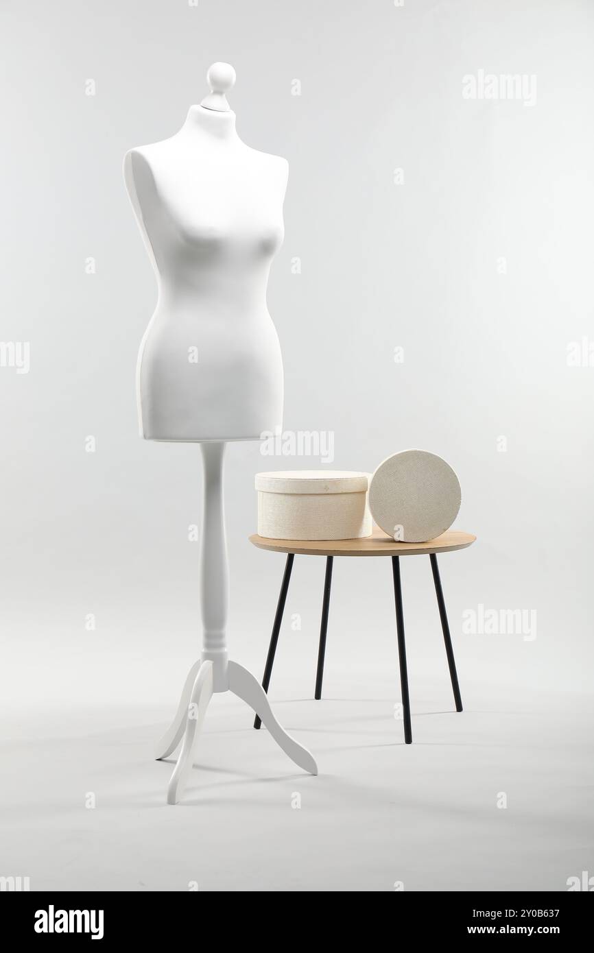 Mannequin and boxes on side table against light grey background ...