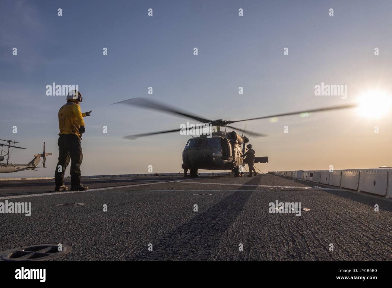 A U.S. Navy Sailor, left, with the amphibious transport dock ship USS ...