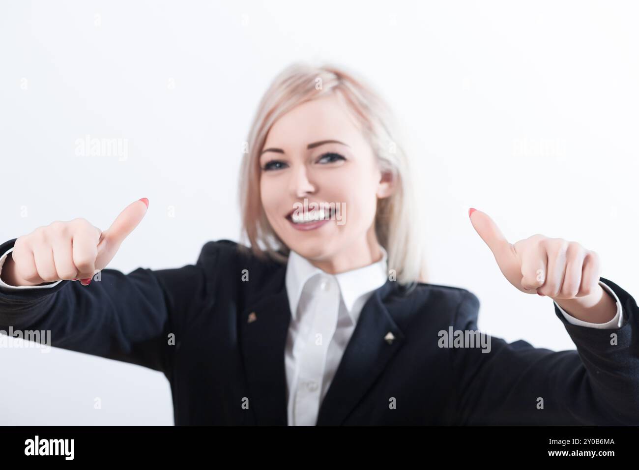 Cheerful businesswoman is gesturing a double thumbs up with a wide ...