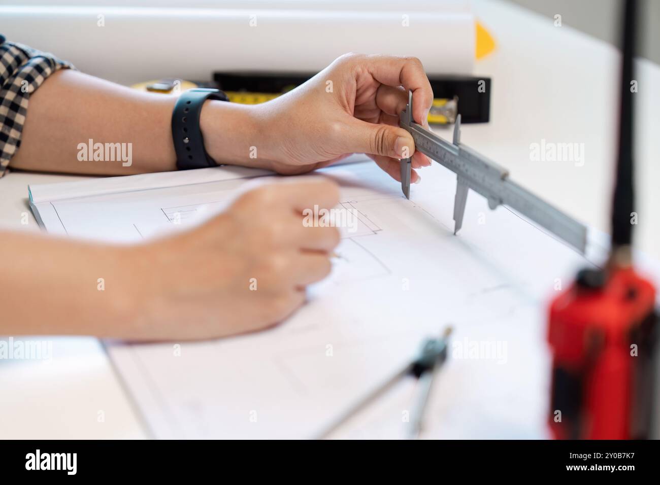 Engineer Measuring Blueprint with Caliper in Modern Office Setting for ...