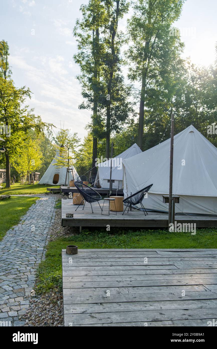 Camping tents set up in a forest with wooden platforms and outdoor ...