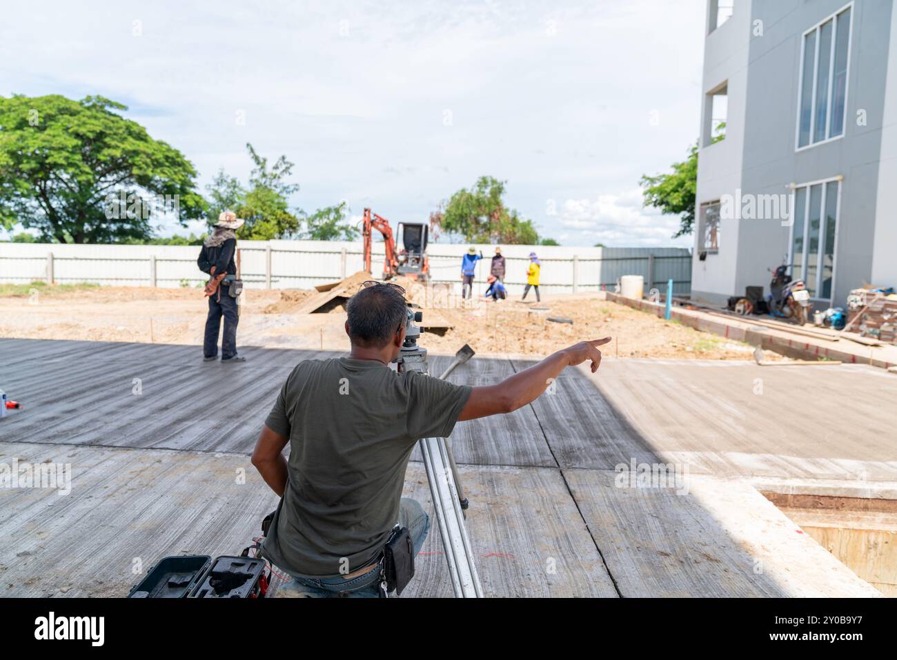 Foreman gives signal to worker while looking through level measuring ...