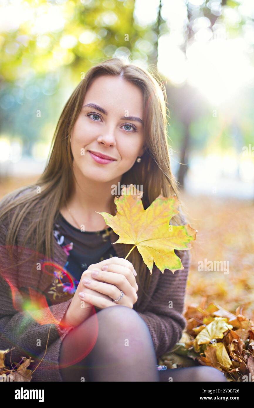 Happy brunette girl posing in autumn park on yellow trees background ...