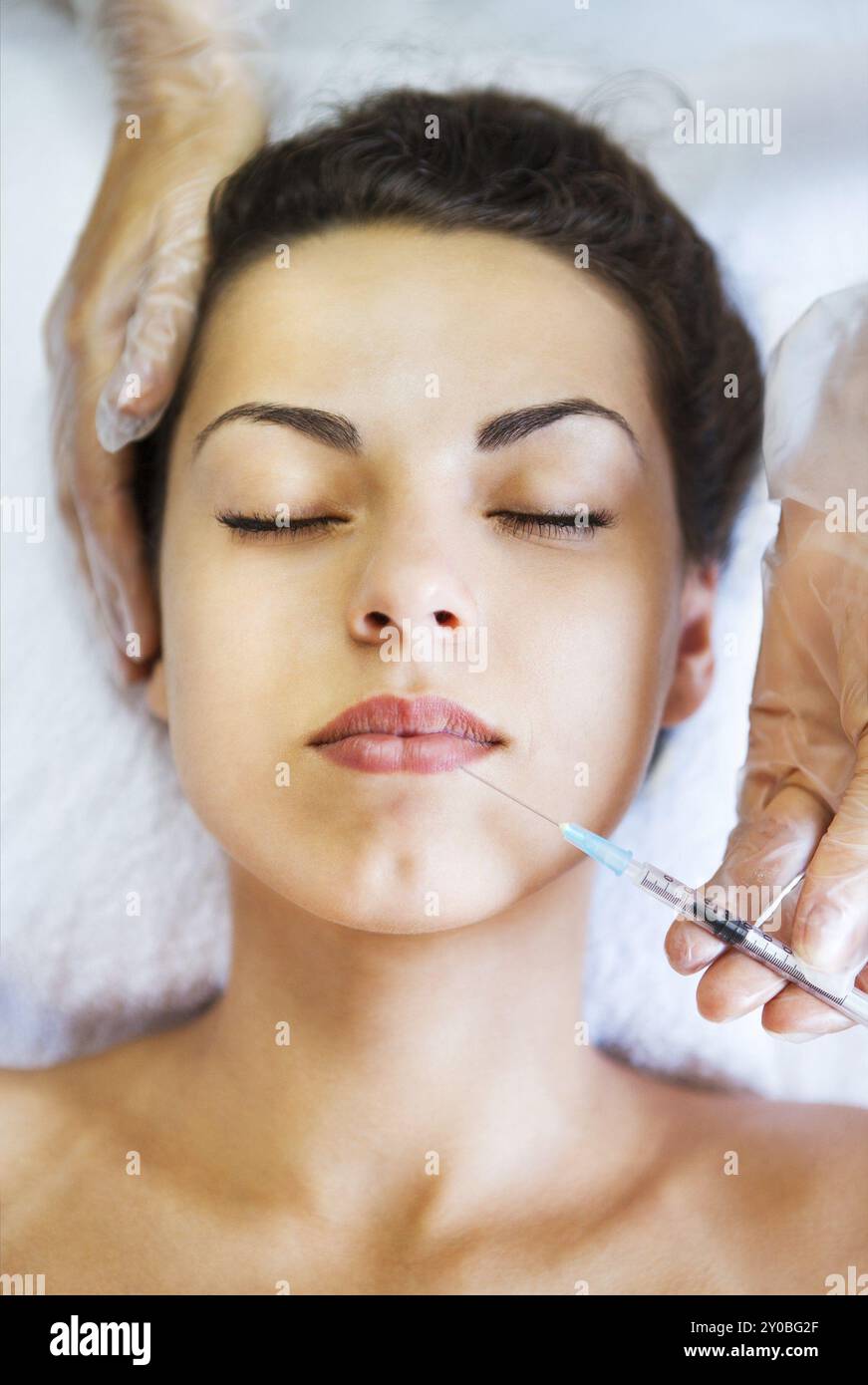 Young pretty woman getting cosmetic injection in the face like a part ...