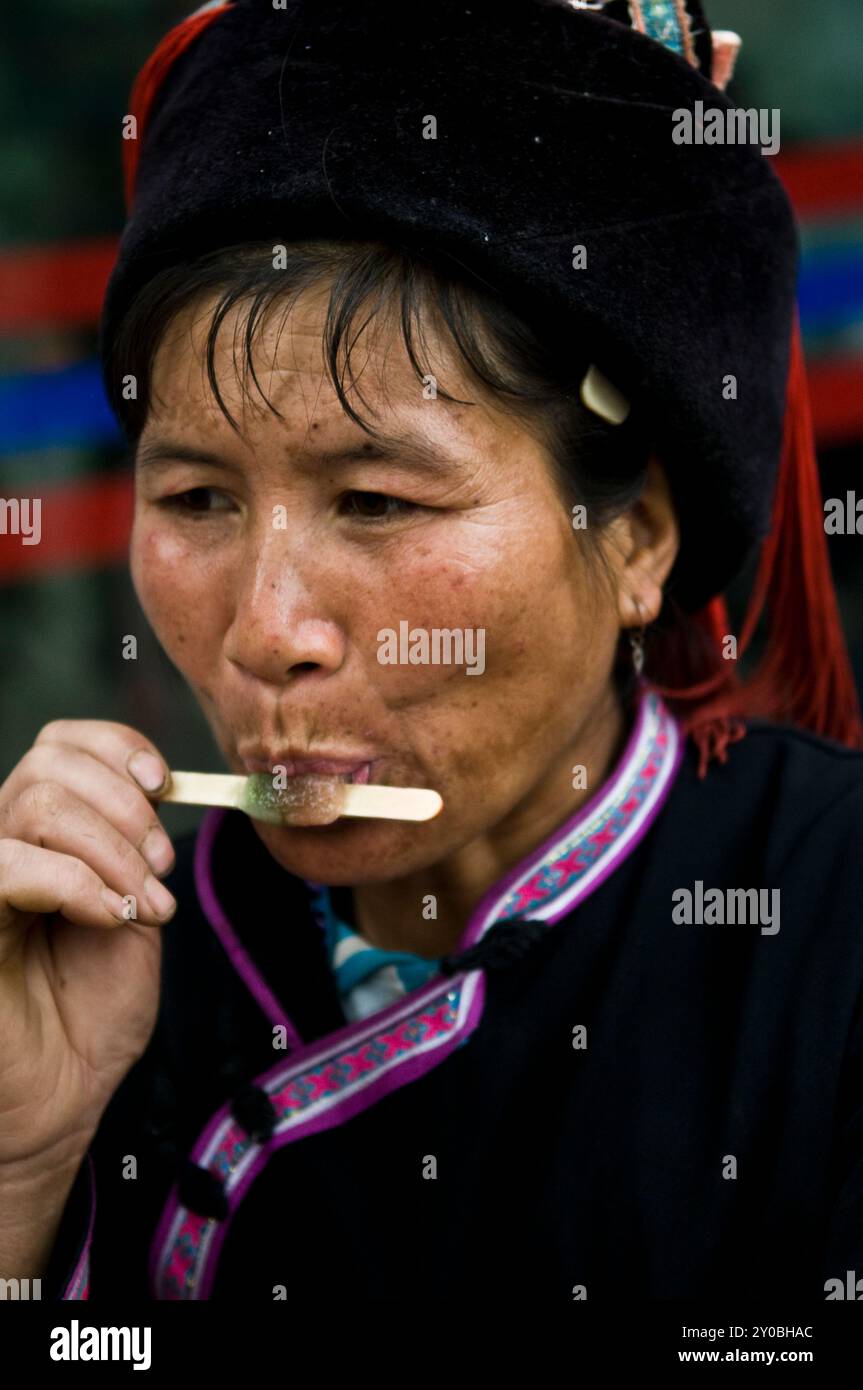 A Black Yao woman eating a popsicle at a local market in southern ...