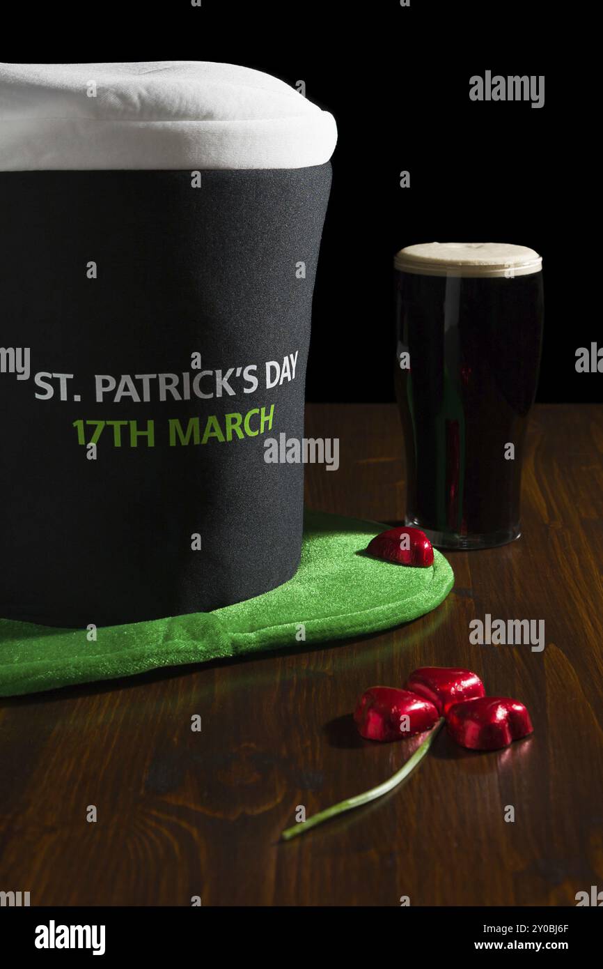 St Patrick day with a pint of black beer, hat and shamrock over a table ...
