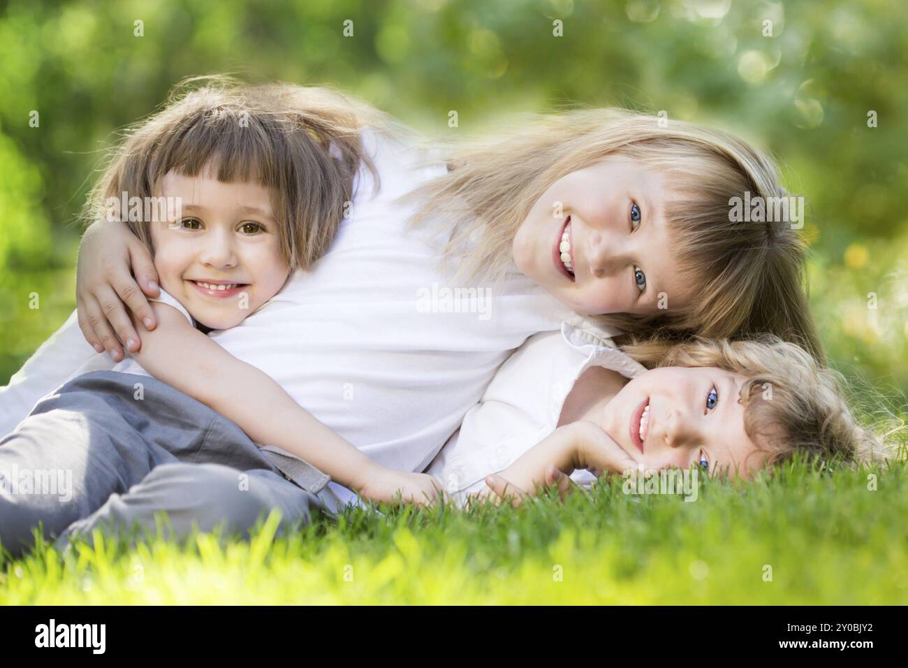 Happy smiling kids playing on green grass in spring park Stock Photo ...