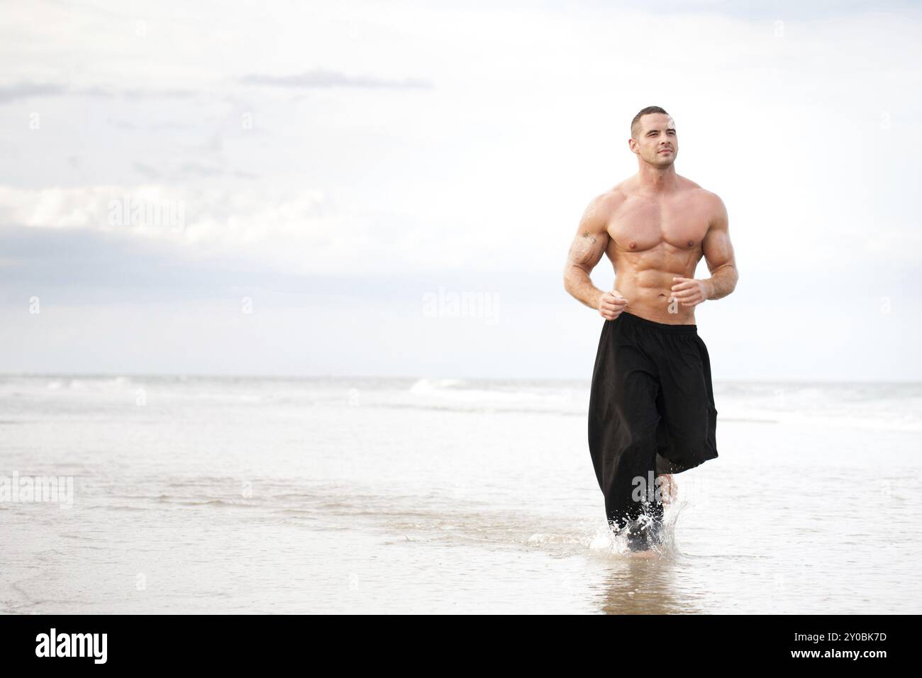 Physically fit man running on the beach Stock Photo - Alamy
