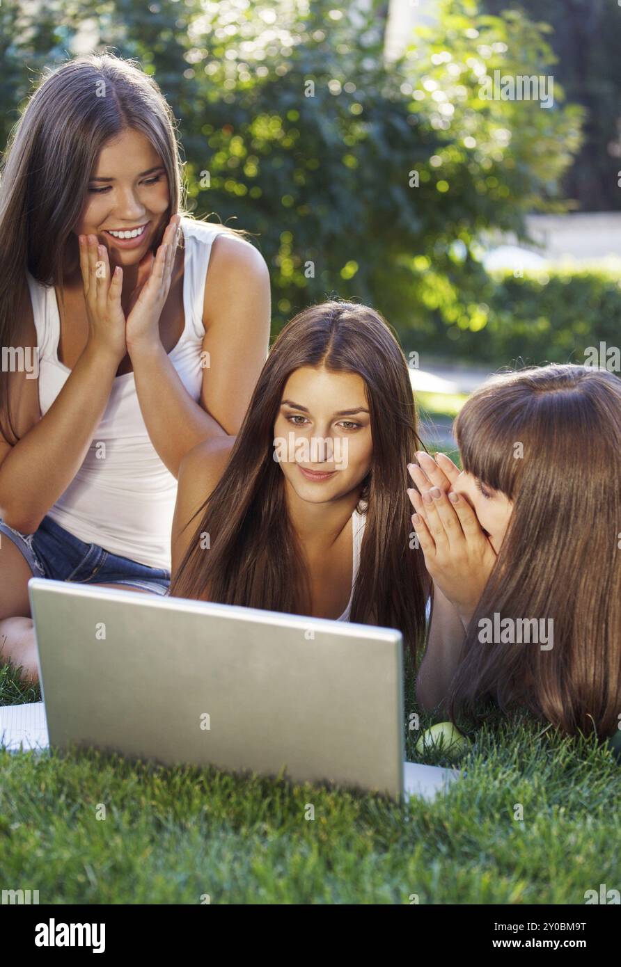 Happy young student girls having fun using a laptop outdoors Stock ...