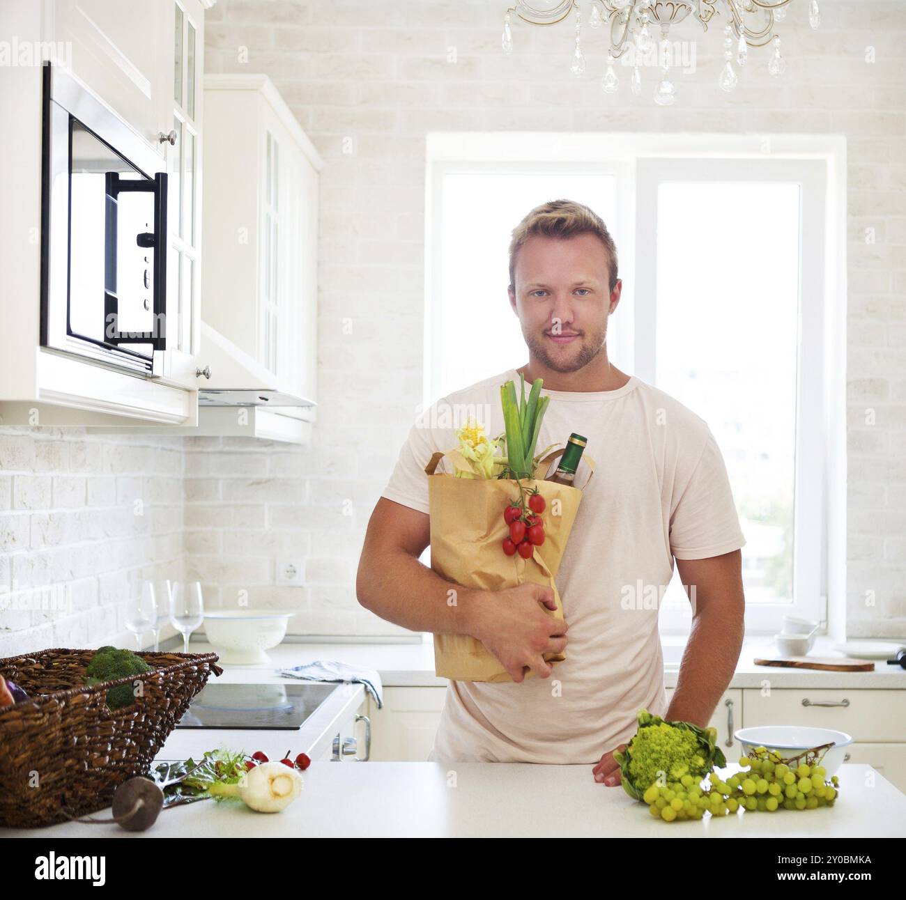 Man holding paper bag full of groceries on the kitchen background ...