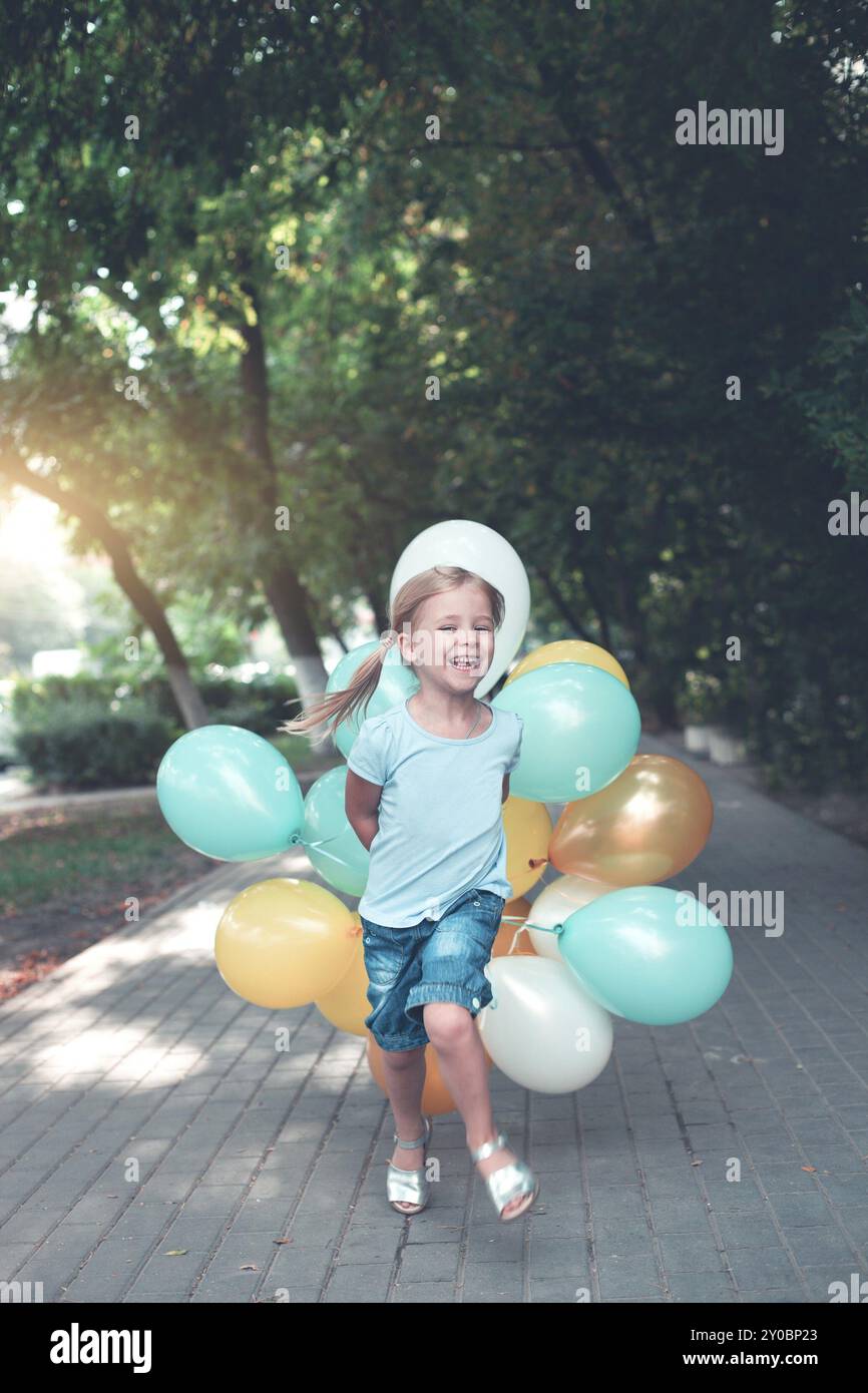 Happy little girl with bunch of colorful balloons running and having ...
