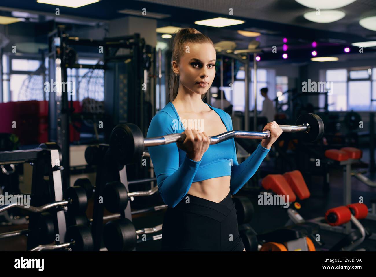 A young woman lifts weights in a modern gym during a fitness session ...