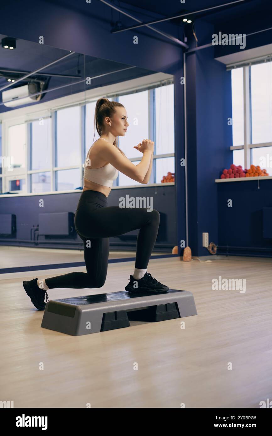 Woman performing step lunges in a modern fitness studio Stock Photo - Alamy