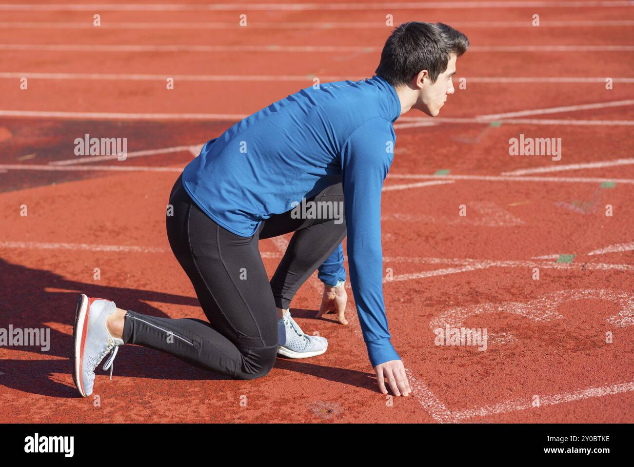 Man athlete on the starting line of a running track at the stadium ...