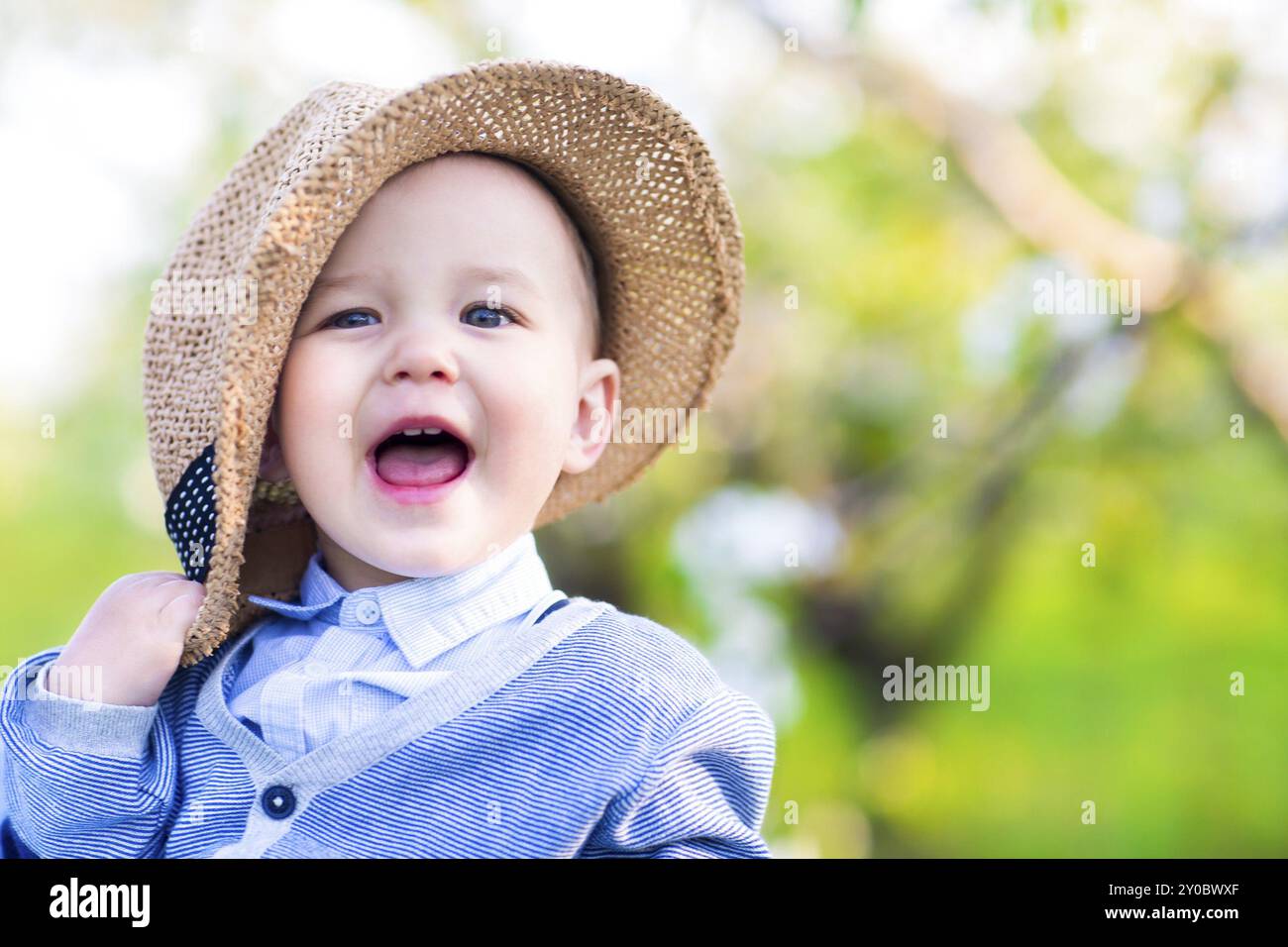 Portrait of a cute happy caucasian baby boy in spring park looks at ...