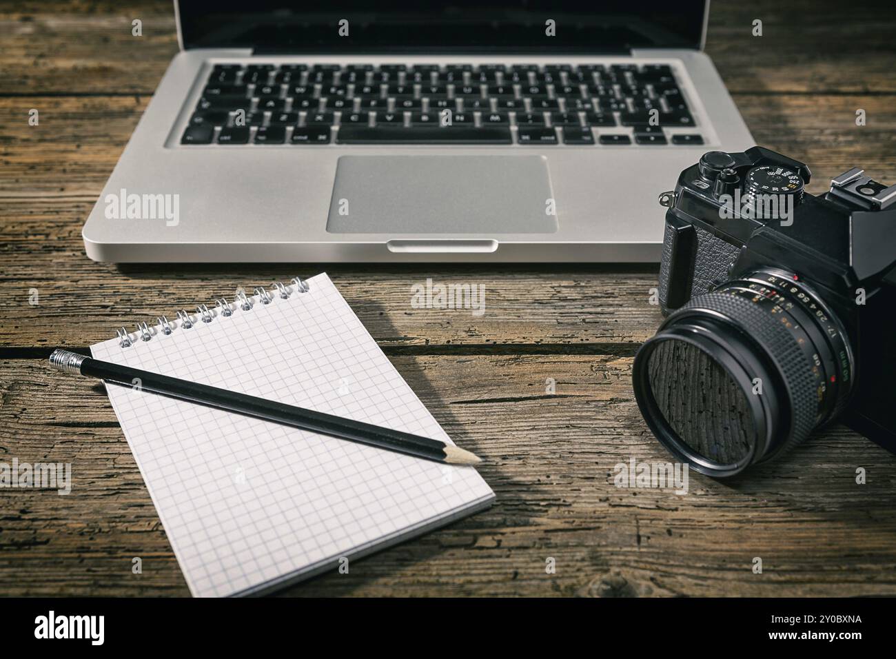 Office workstation with laptop, camera and notebook over an old wooden ...