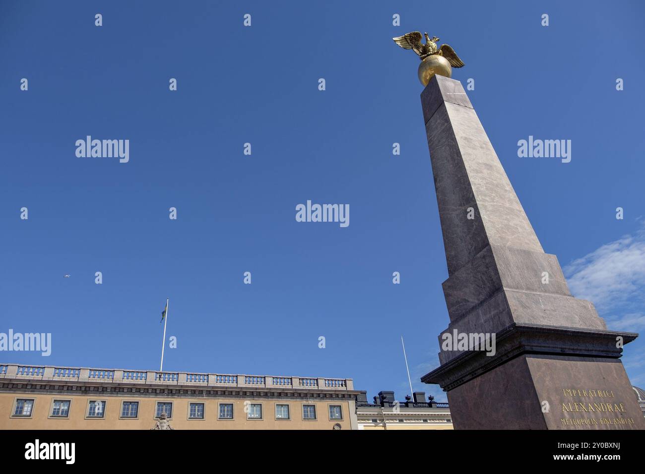 Stone obelisk with golden eagle statue in front of a building under a ...