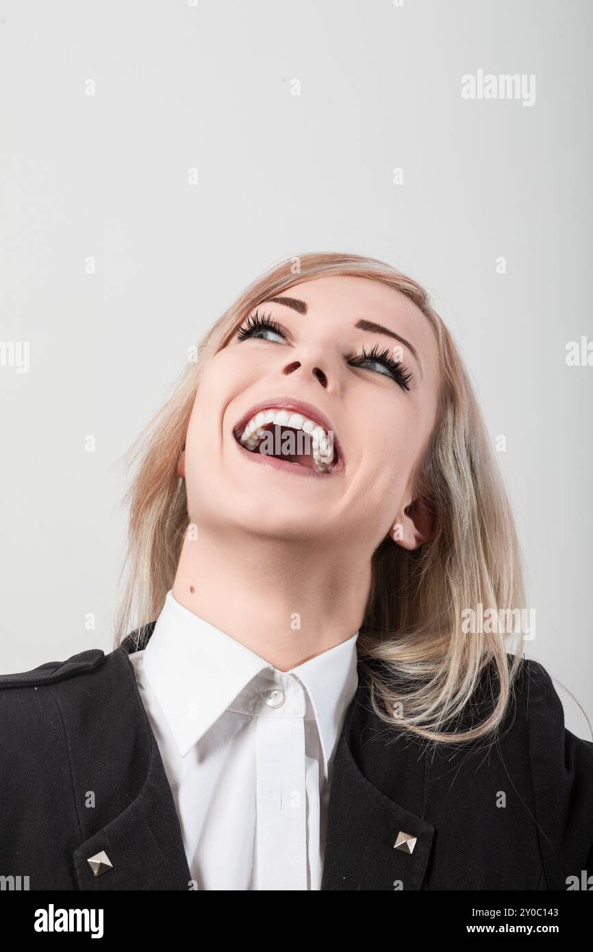 Cheerful young businesswoman is looking up and laughing heartily, her ...