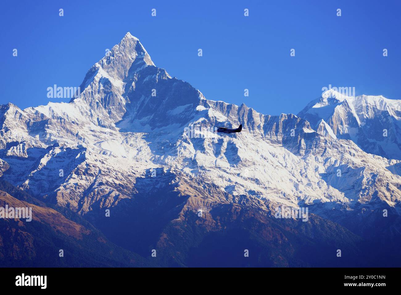 Tourist airplane flying in front of the snow capped peak of ...