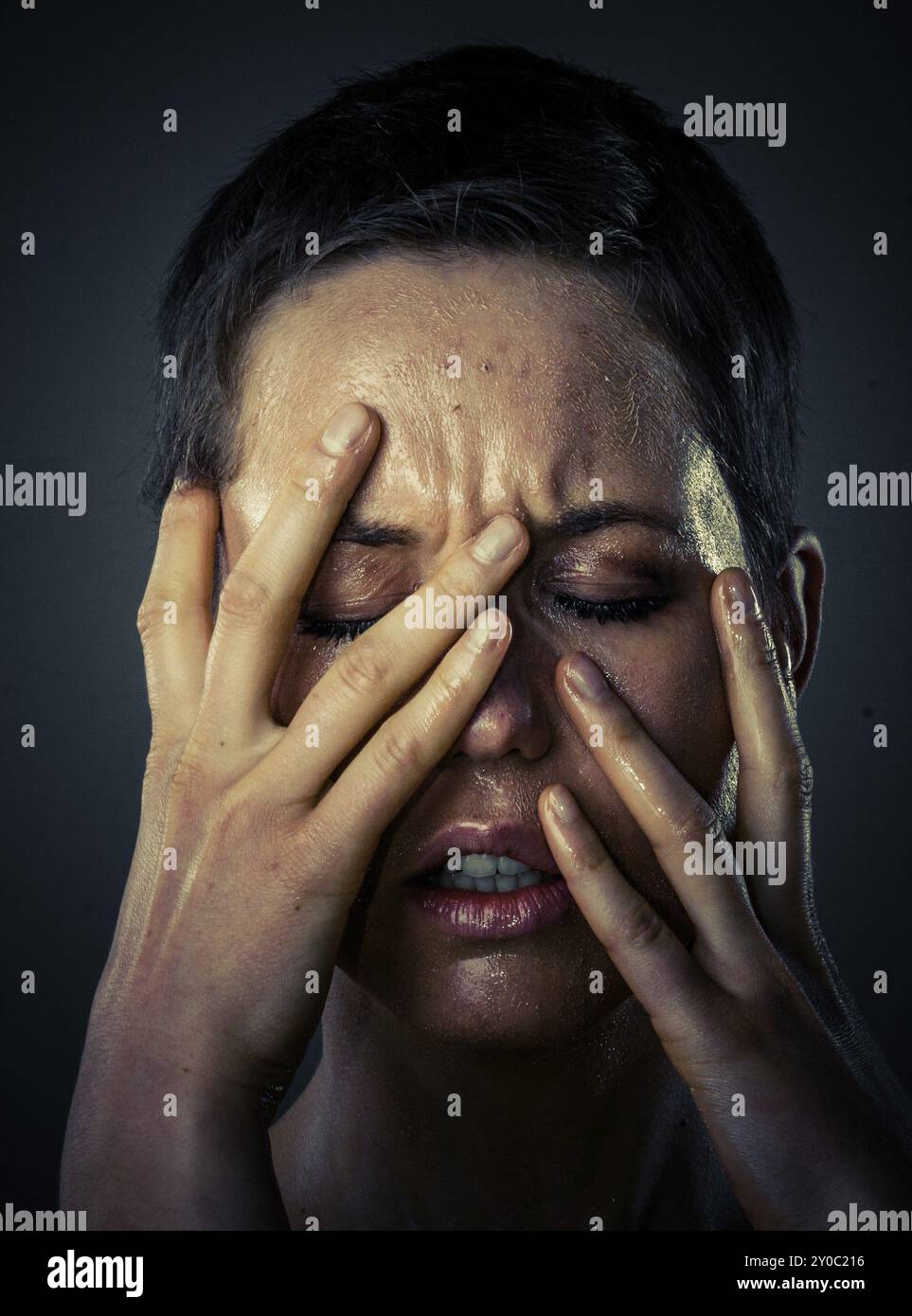 Water runs down the face of a young woman with short hair and closed ...