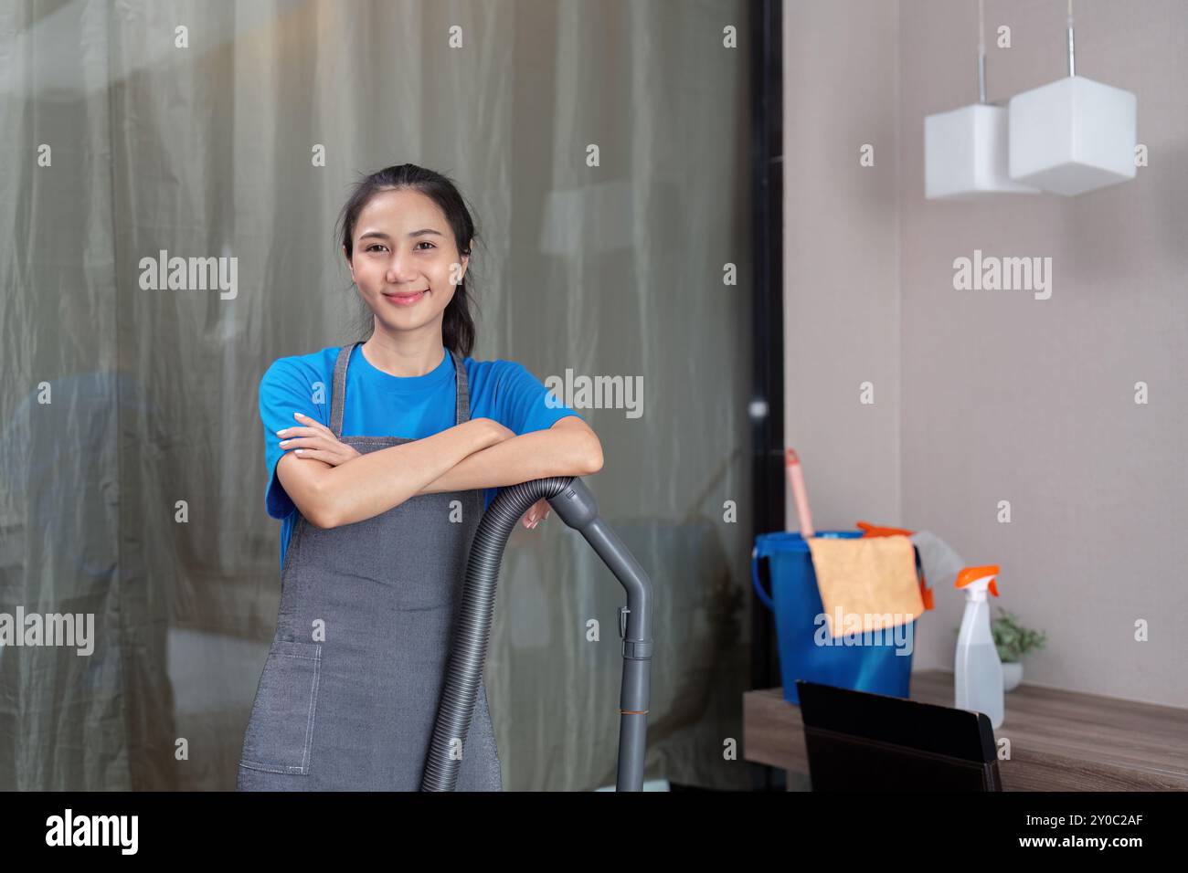 Asian female housekeeper smiling with vacuum in modern home Stock Photo ...