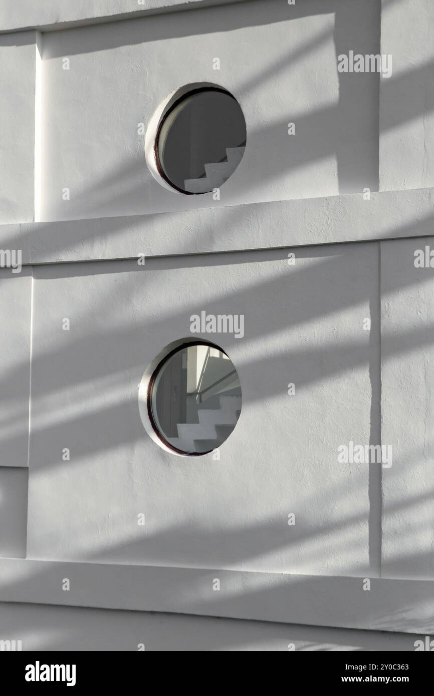 Round circle shaped windows on a white painted building with sunset ...