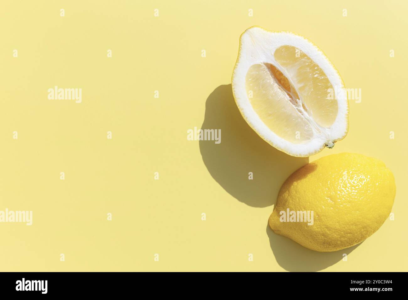 Two halved cuts of lemon with shadow on yellow background. Healthy ...