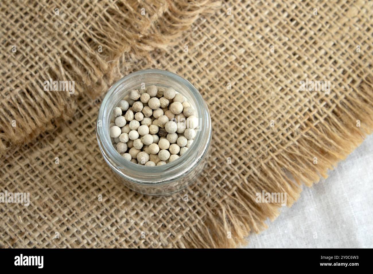 Spices, white peppers, pepper seeds sprinkled on white textured ...