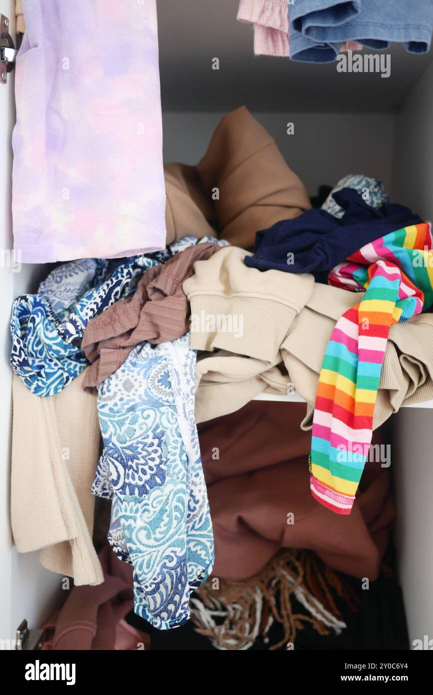 Messy closet with piled clothes and colorful accessories, displaying ...
