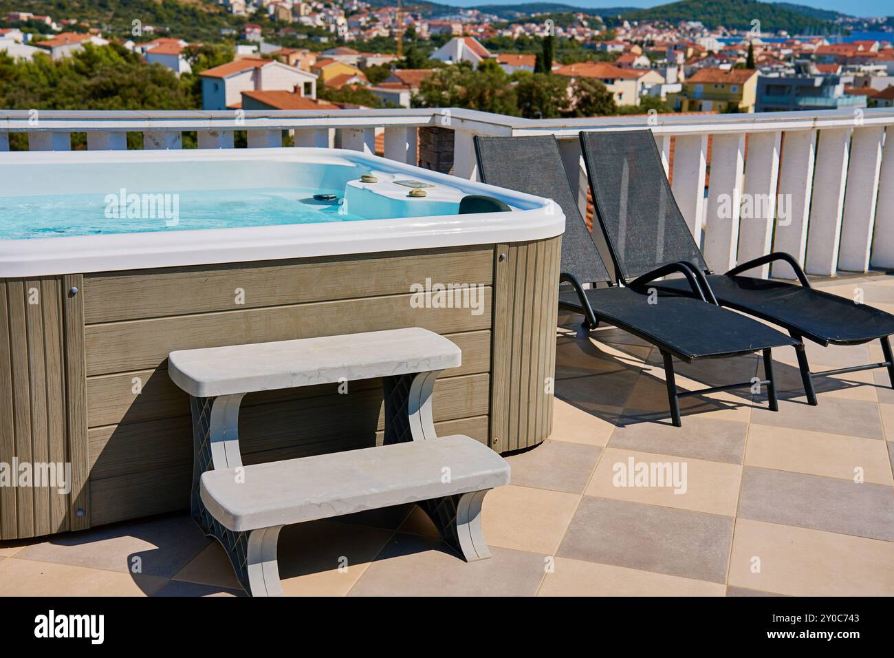 Outdoor hot tub on sunny rooftop deck with bubbling water and ...
