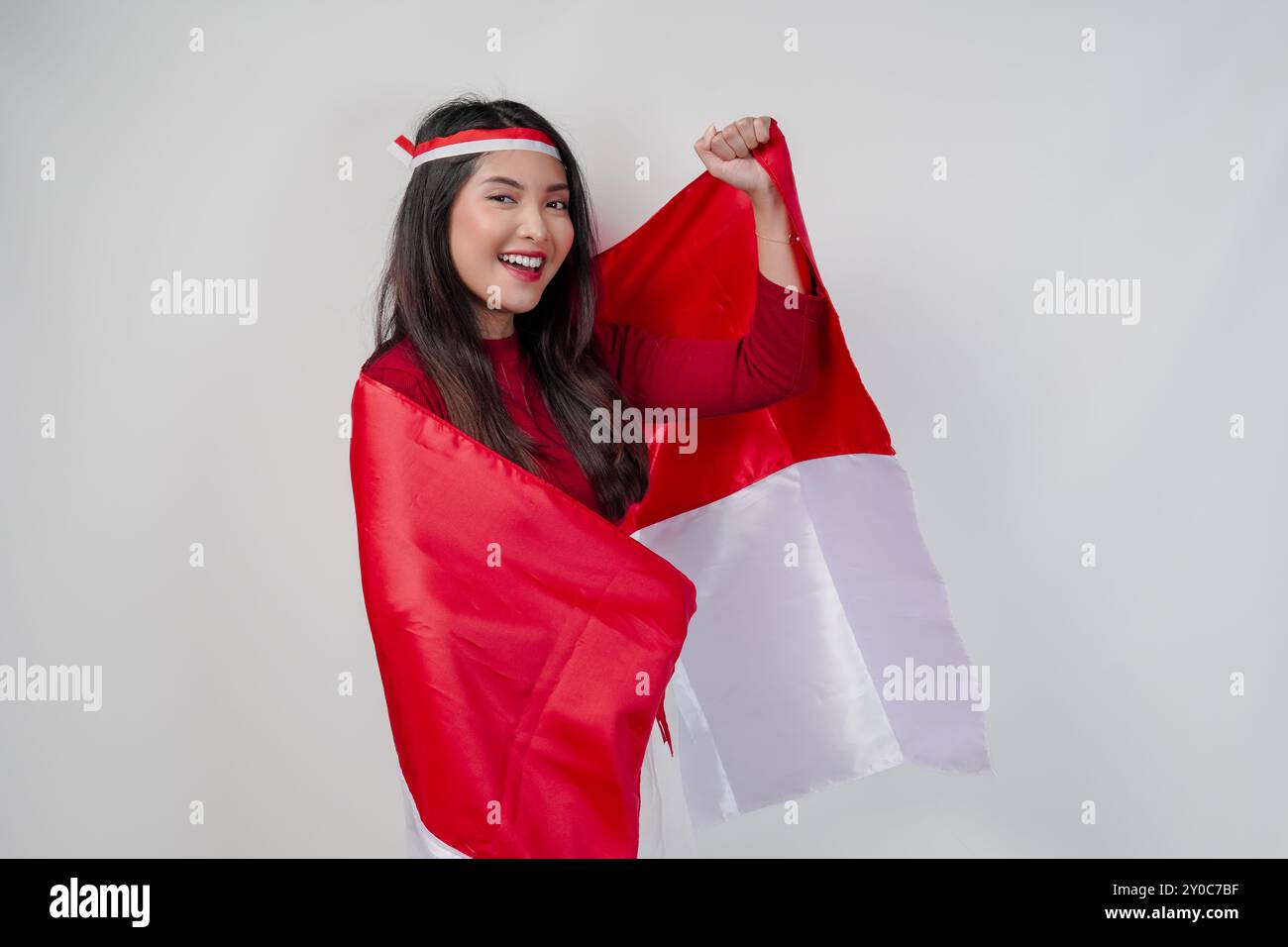 Happy young Asian woman with Indonesia flag draped over her shoulders ...