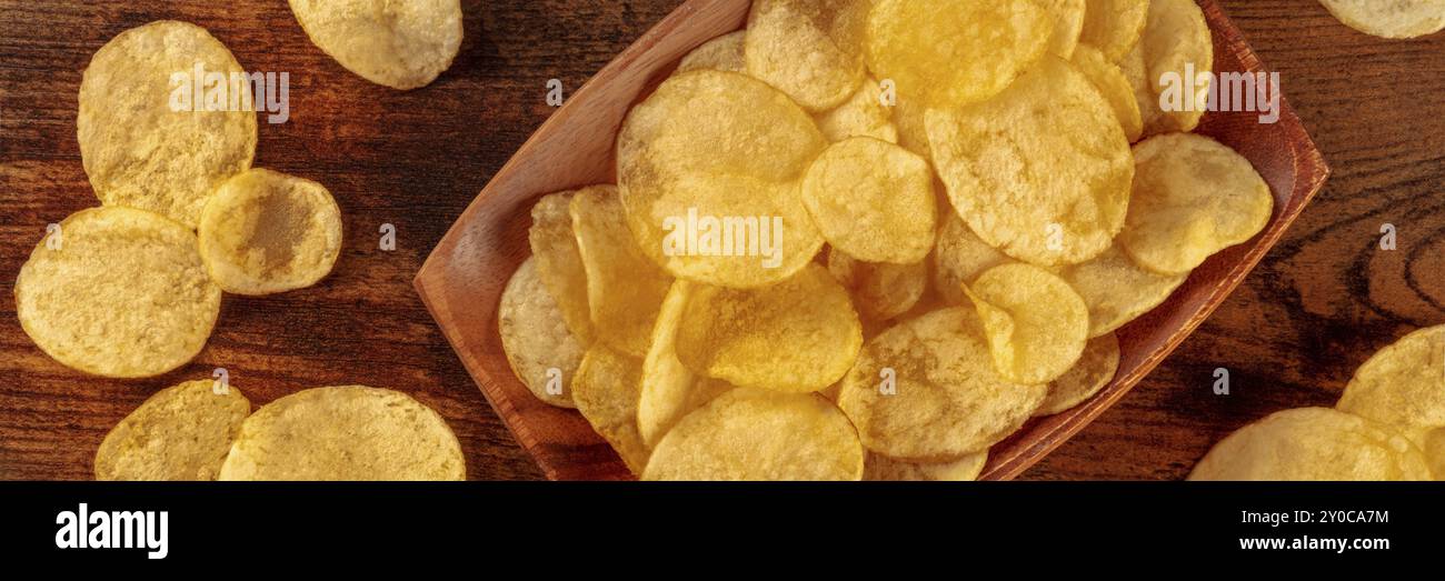 Potato chips or crisps, a salty snack on a wooden background, a ...
