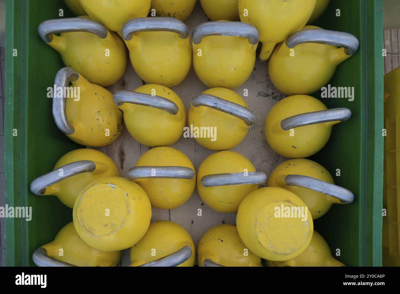 Zenithal view of a collection of yellow kettlebells of varying weights ...