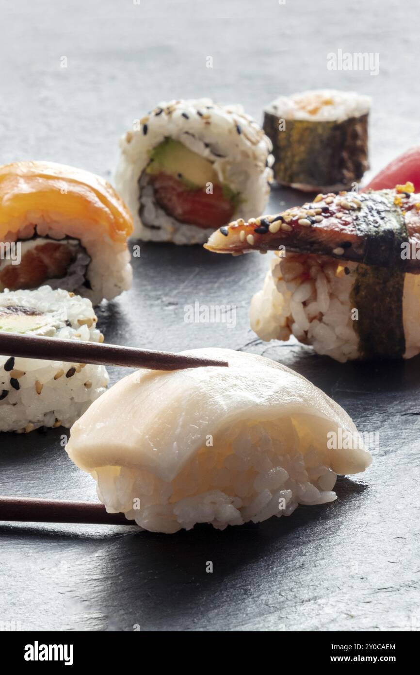 Sushi with chopsticks. Whitefish nigiri and rolls on a black background ...