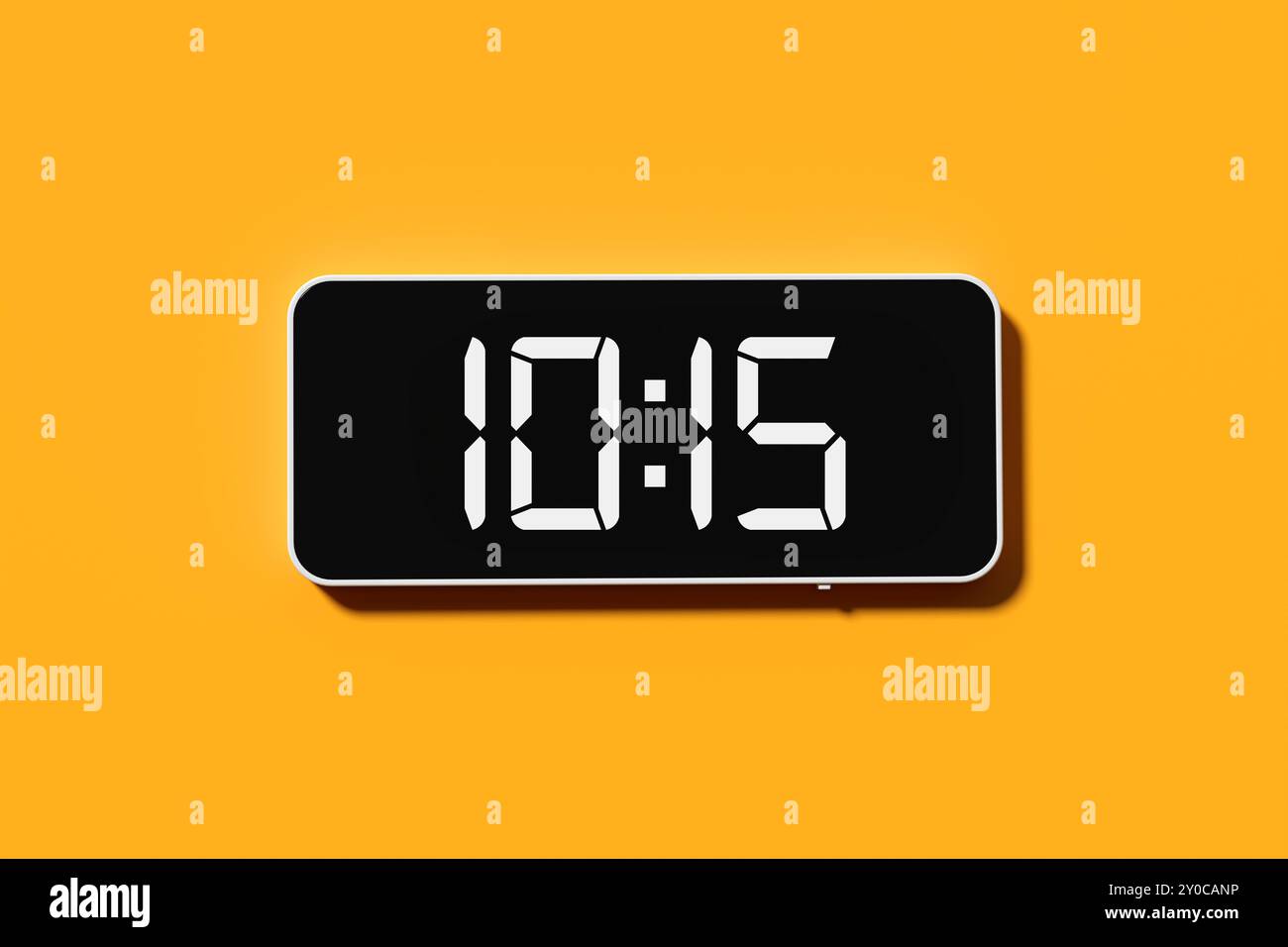 Black digital alarm clock displaying 10:15, on a vibrant yellow ...