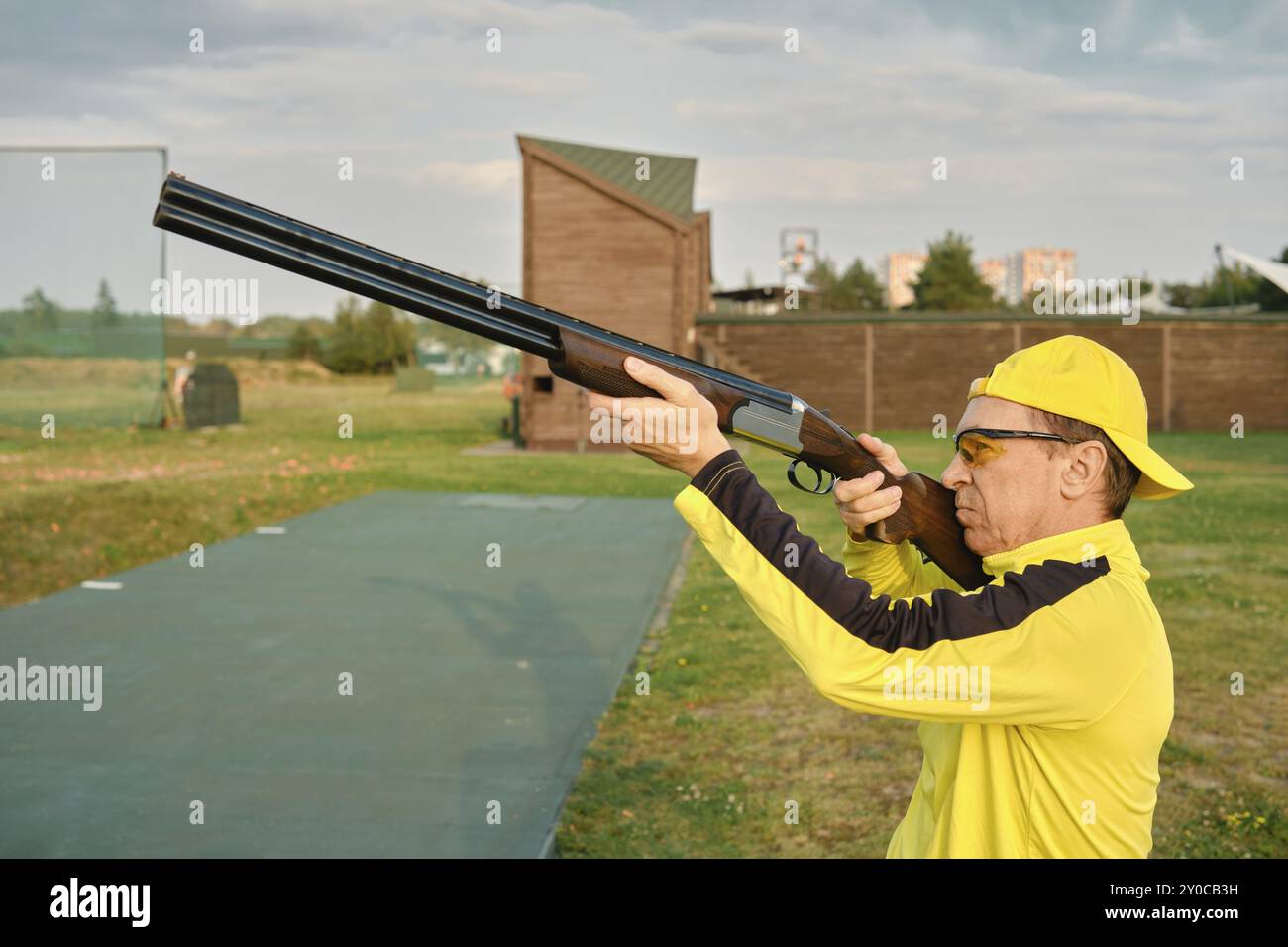 An old man shooting at an outdoor shooting range with a shotgun in hand ...