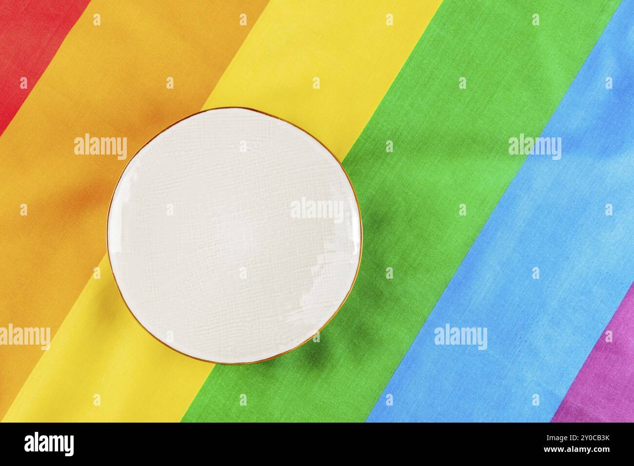 Gay dinner concept. A plate, shot from the top on the LGBT rainbow flag ...