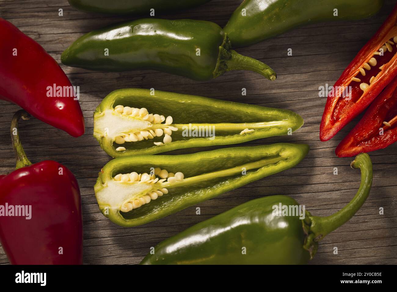 An overview of whole and sliced red and green peppers on wood Stock ...