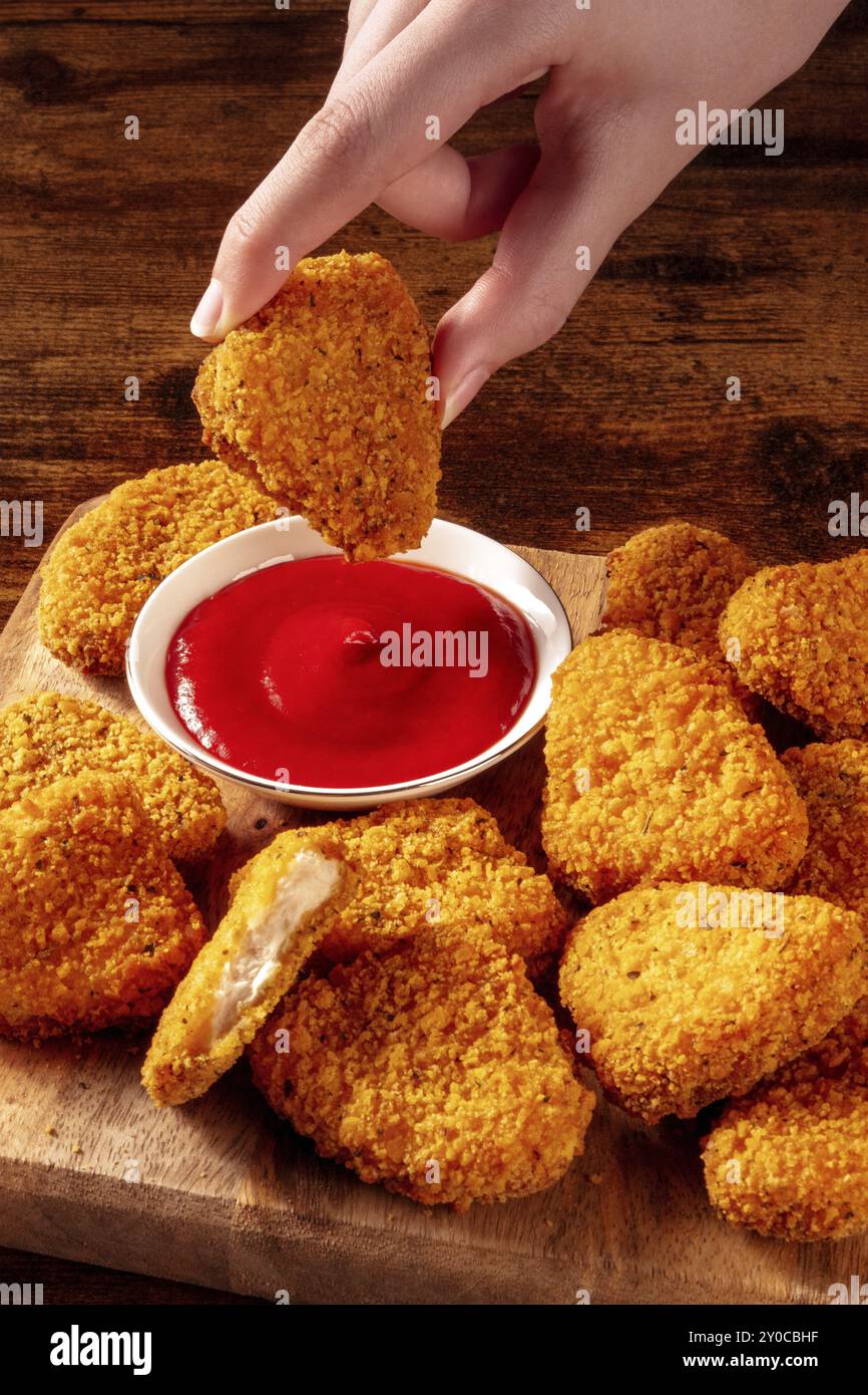Chicken nugget dipped in ketchup close-up. A crispy snack at a ...