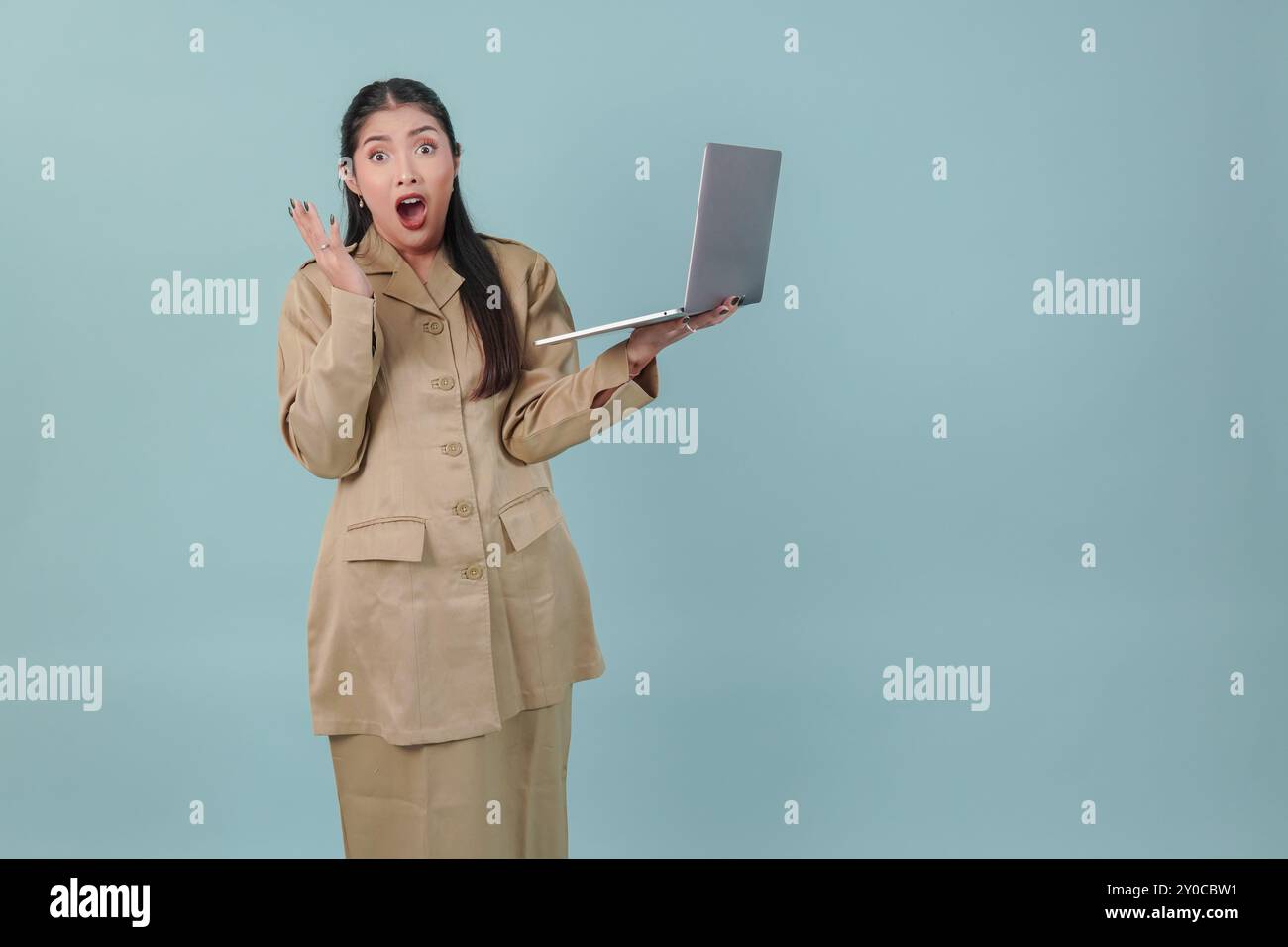 Surprised Indonesian government worker woman holding her laptop with ...