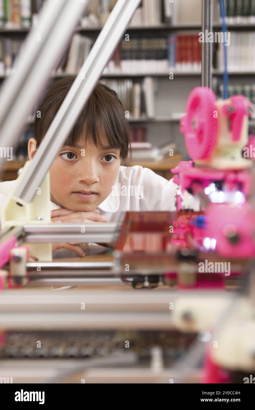 A young girl watches as a 3D printer prints an object Stock Photo - Alamy