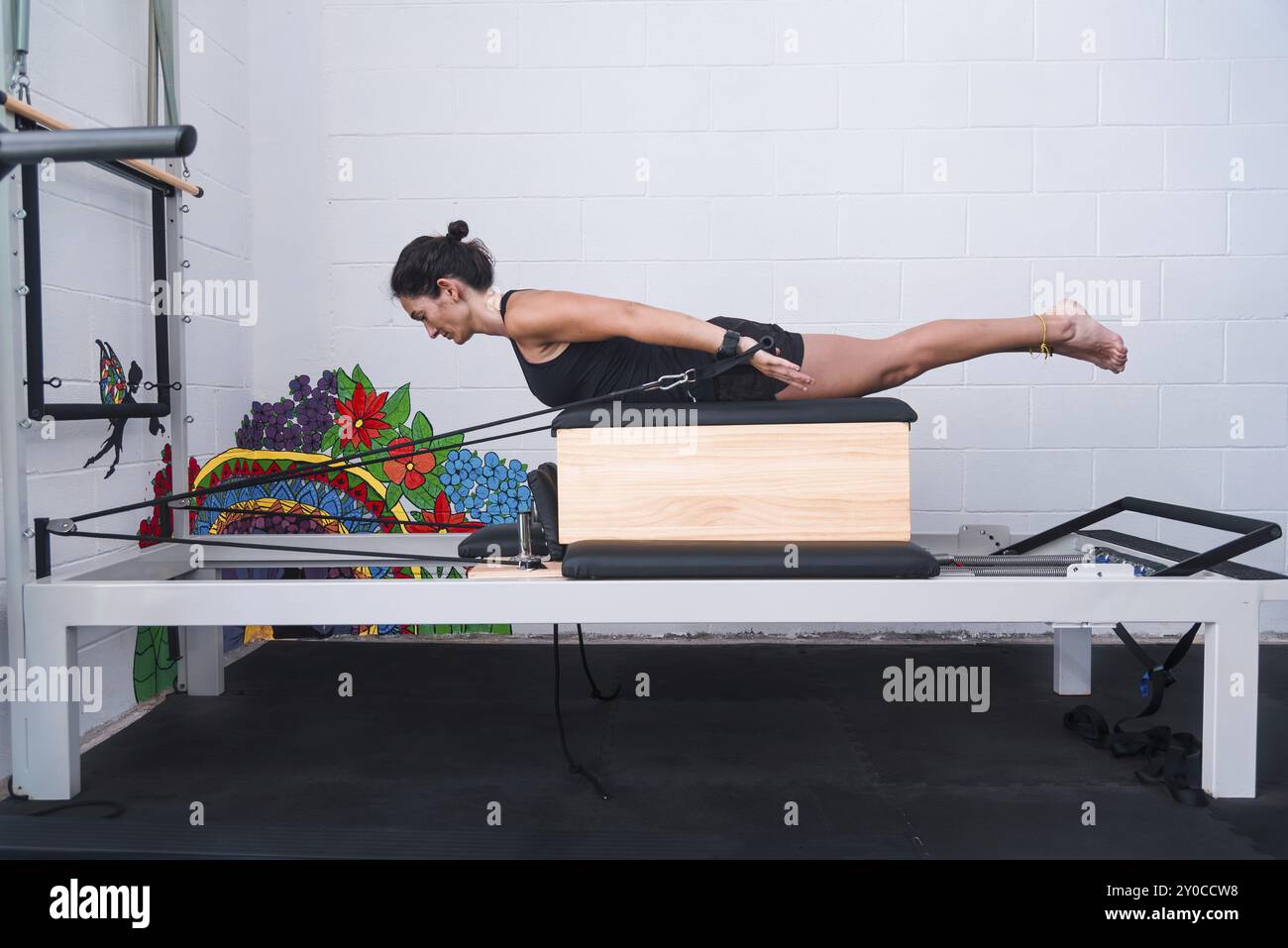 A woman performing a modified plank exercise on a Pilates reformer in a ...