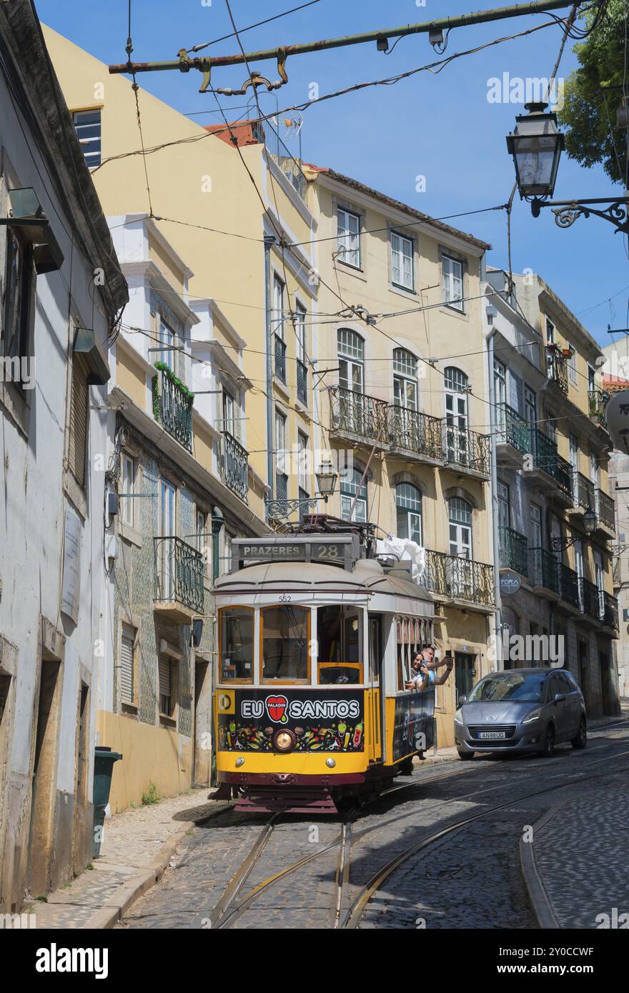 Yellow tram runs through narrow streets with historic buildings under a ...