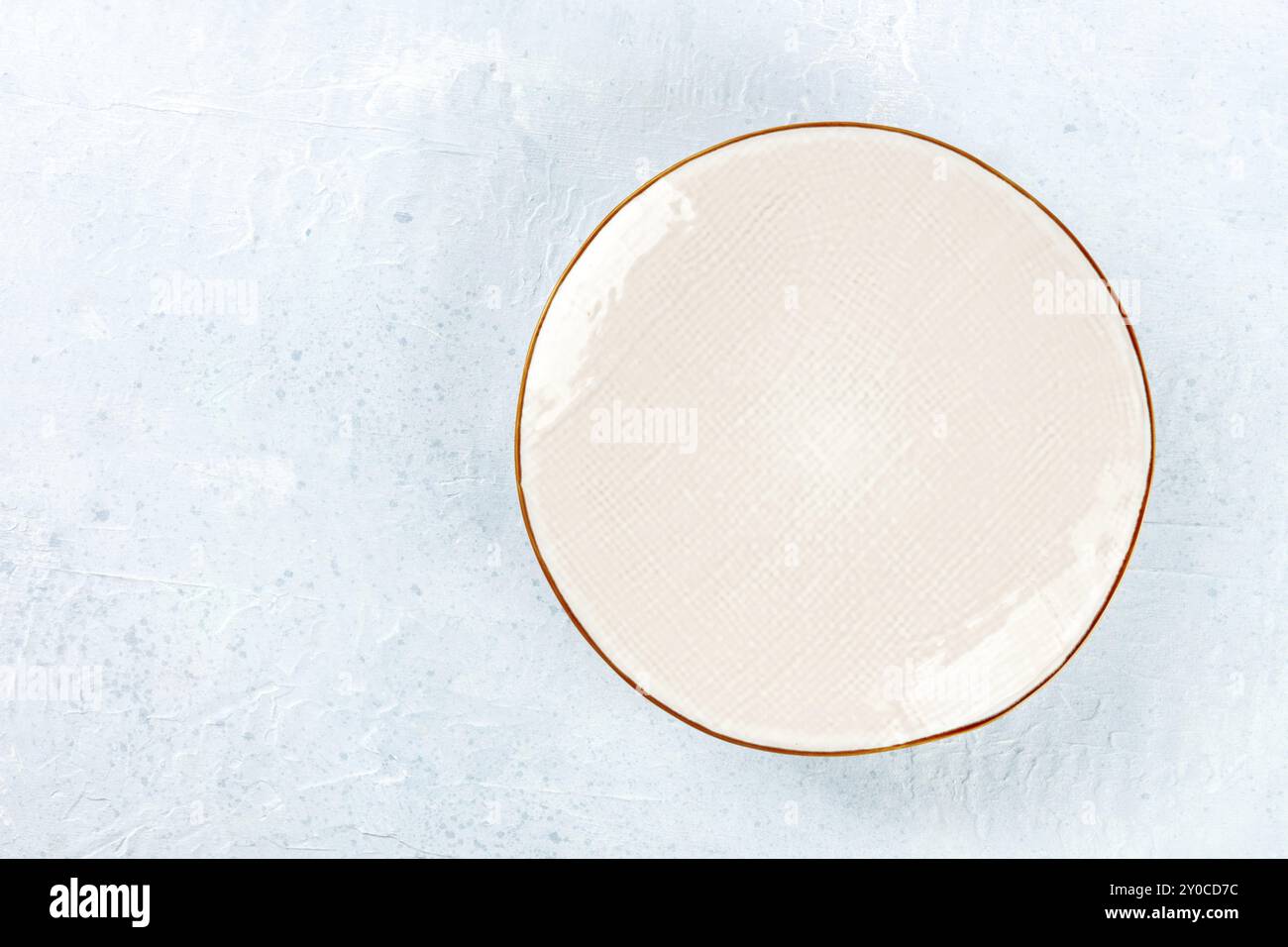 An empty white plate with a gold rim, shot from above on a slate ...